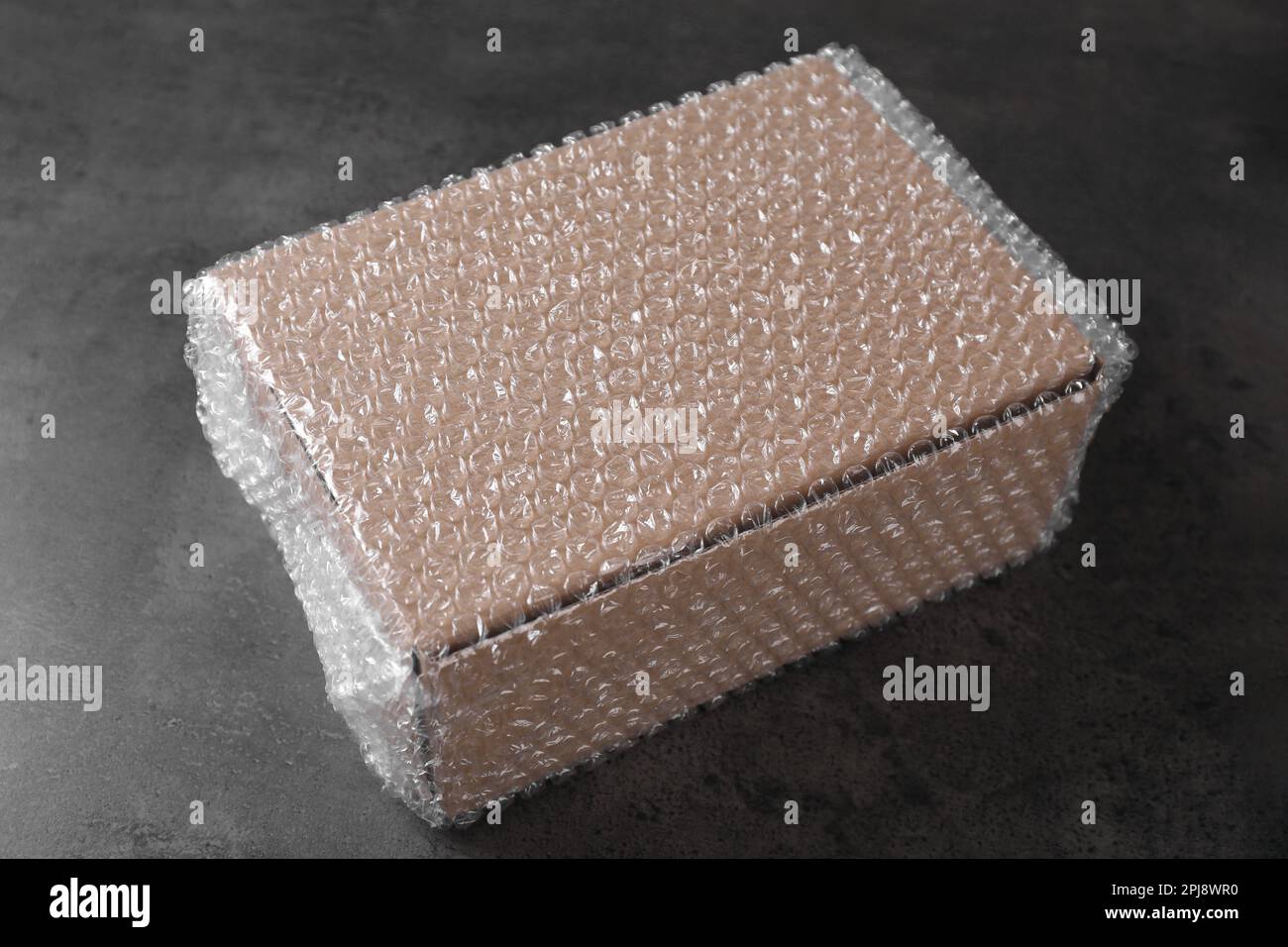 Cardboard box covered with bubble wrap on dark grey table Stock Photo ...