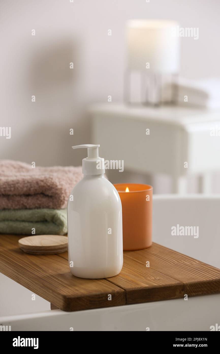 Tray with bottle of bubble bath, towels and candle on tub in bathroom ...