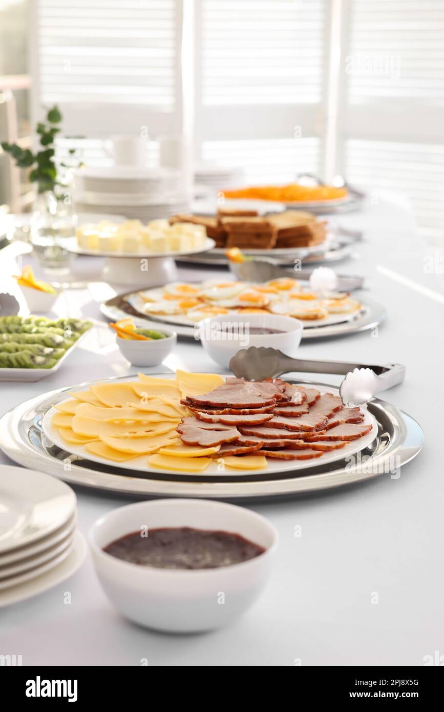 Different meals for breakfast on white table indoors. Buffet service ...
