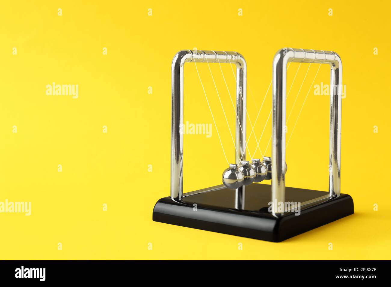 Newton's cradle on yellow background, space for text. Physics law of ...