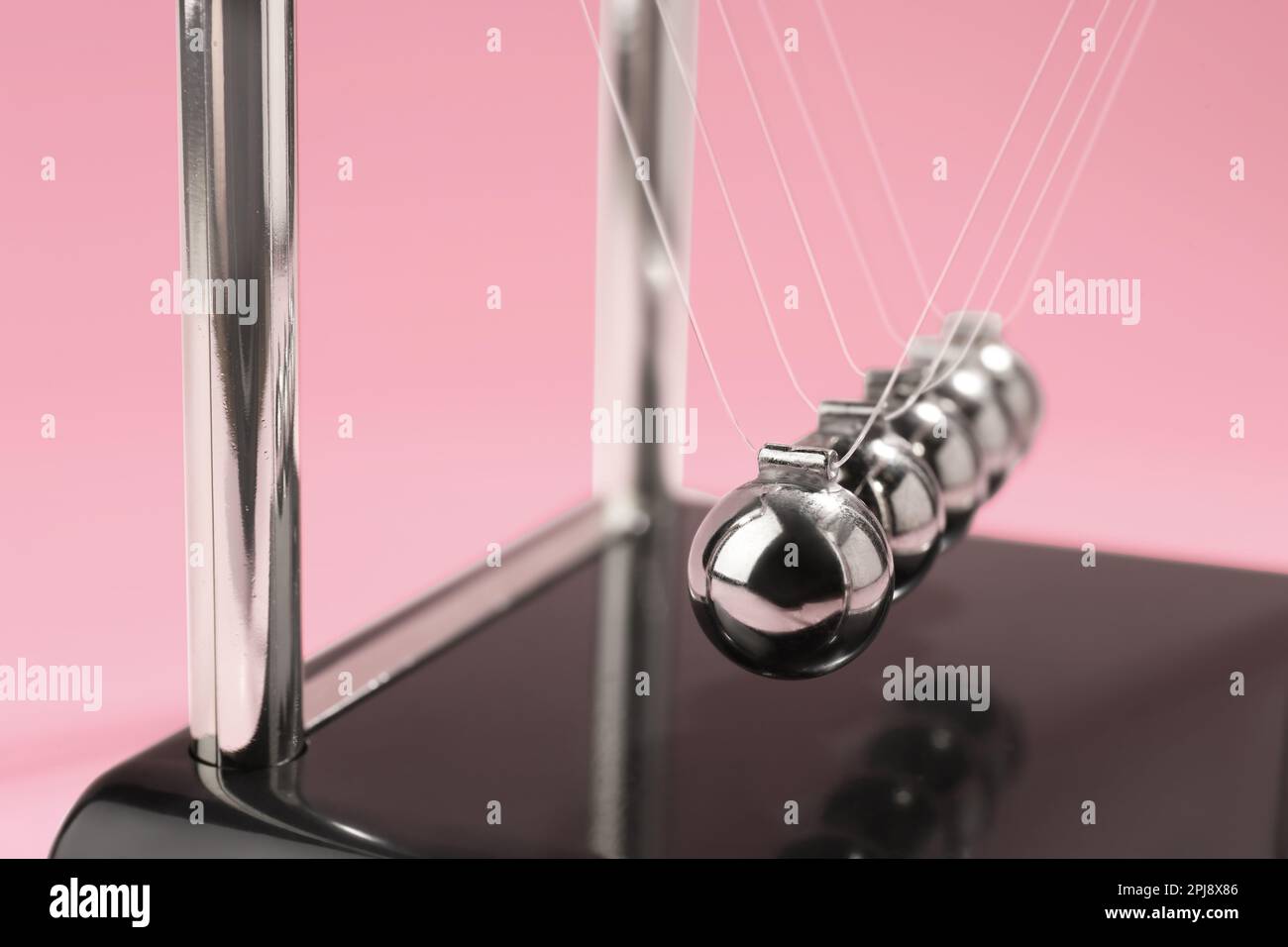 Newton's cradle on pink background, closeup. Physics law of energy ...