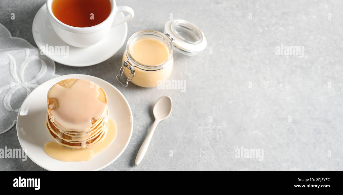 Composition with pancakes and condensed milk on grey background, space ...