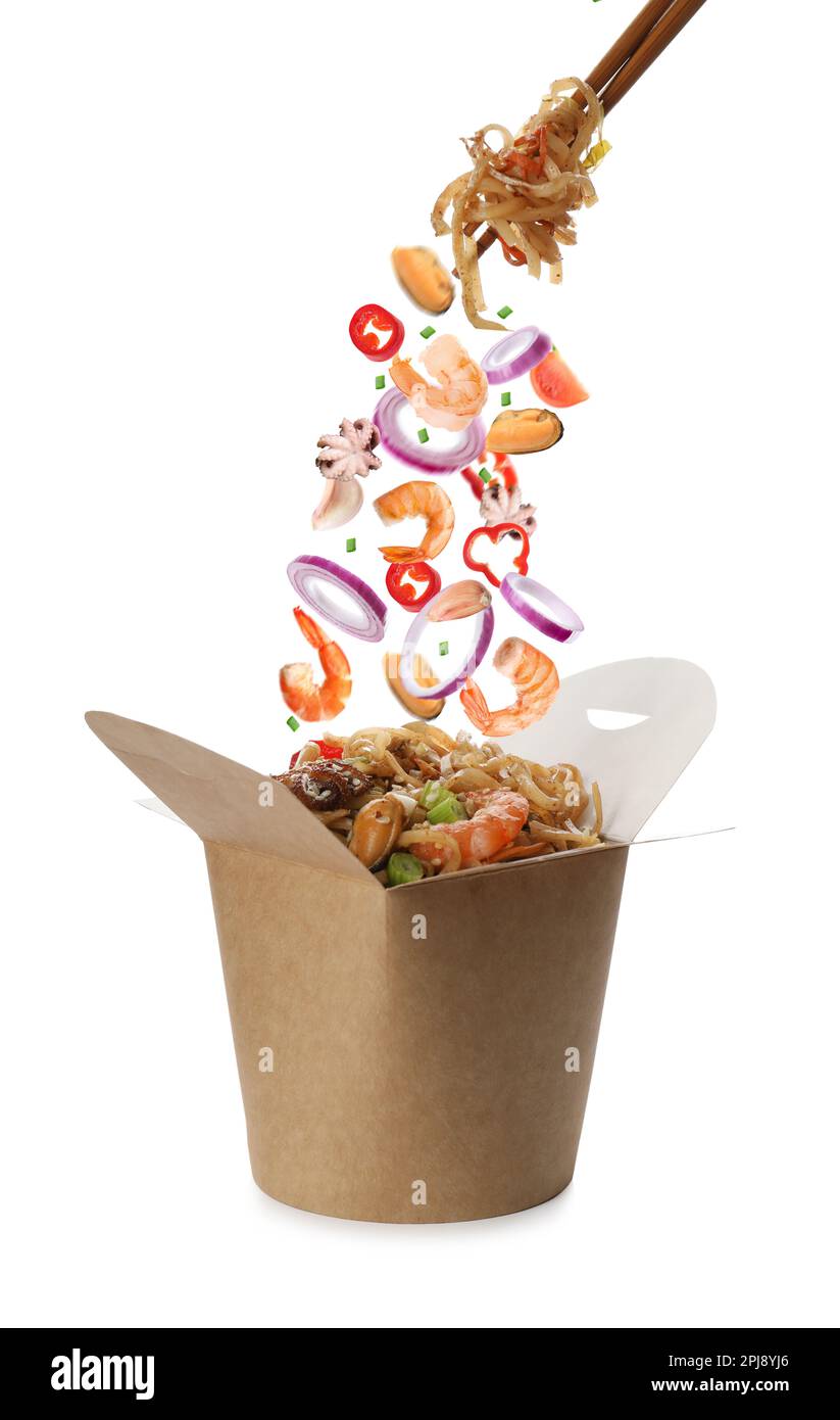 DIfferent fresh ingredients falling into box of wok noodles on white ...