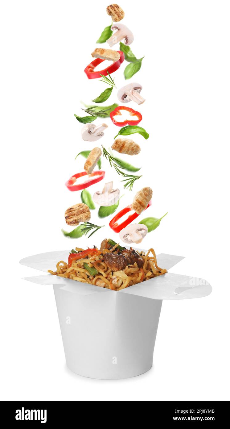 DIfferent fresh ingredients falling into box of wok noodles on white ...