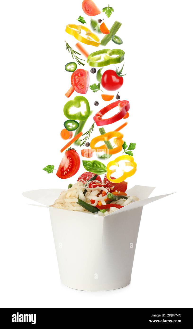 DIfferent fresh ingredients falling into box of wok noodles on white ...
