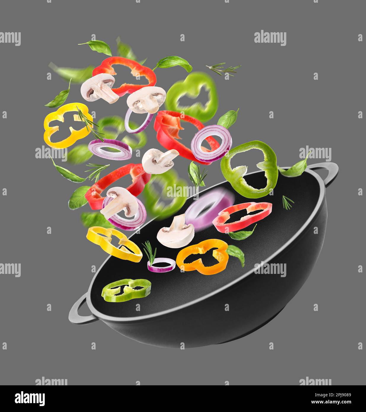 Different tasty ingredients falling into wok on light grey background ...