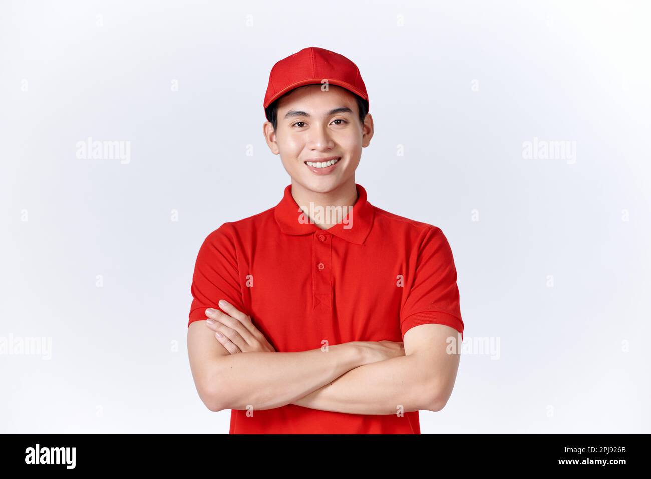 Smiling friendly-looking asian delivery guy in blue uniform cross arms ...