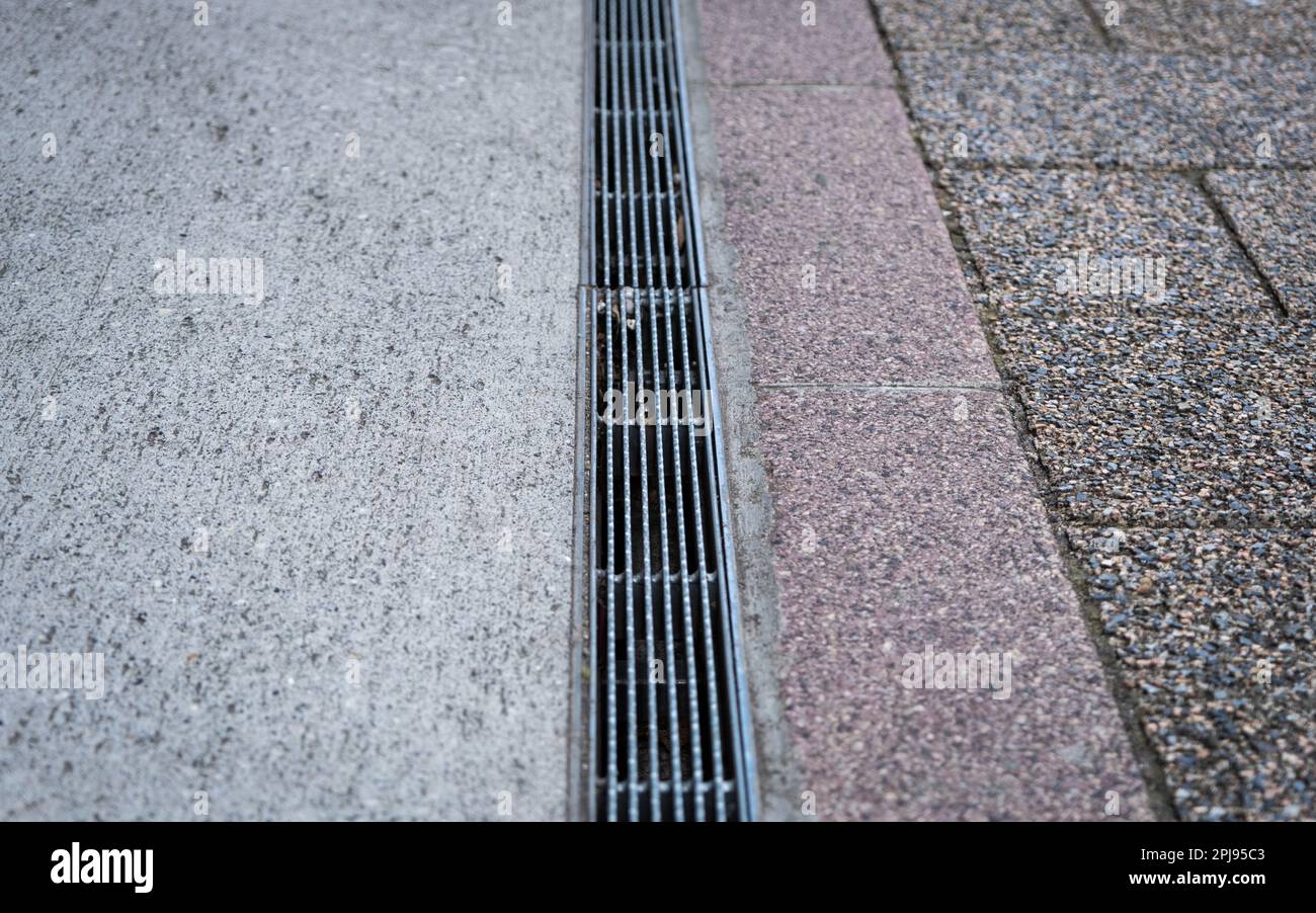 Stainless steel grated flood water storm drain on a Tokyo sidewalk ...