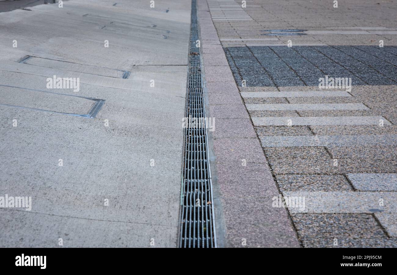 Stainless steel grated flood water storm drain on a Tokyo sidewalk ...
