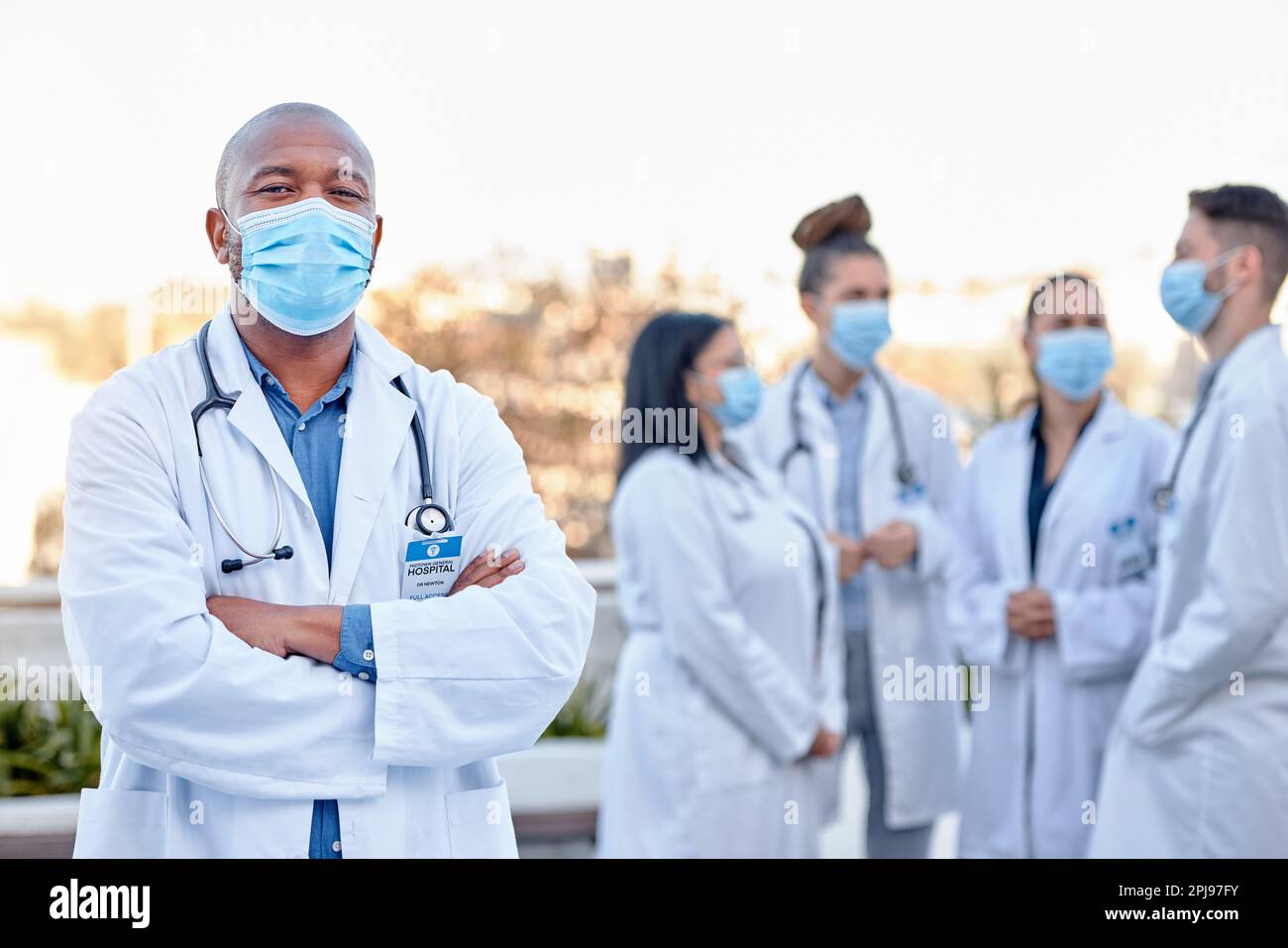 Covid, portrait and proud man doctor outside of hospital with team for ...