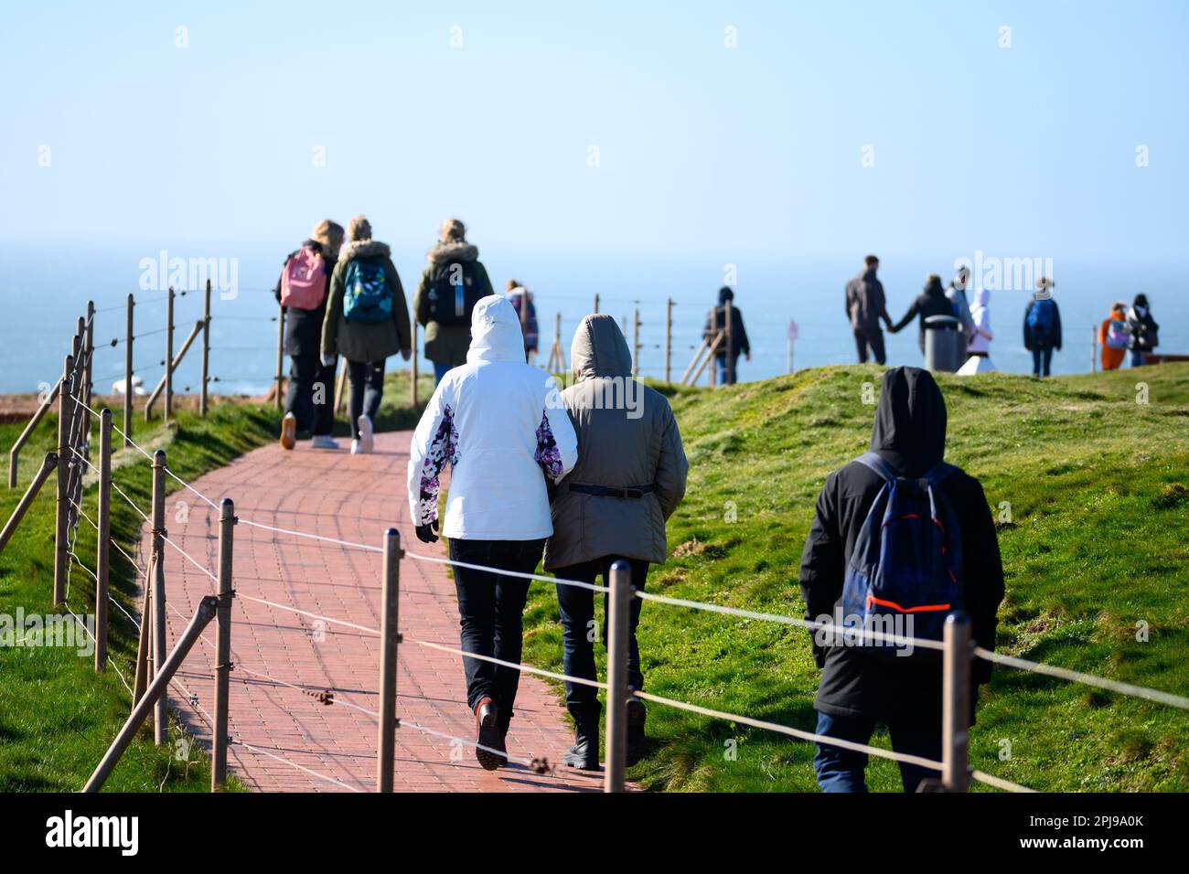 24 March 2023, Schleswig-Holstein, Helgoland: Walkers walk on a path by ...