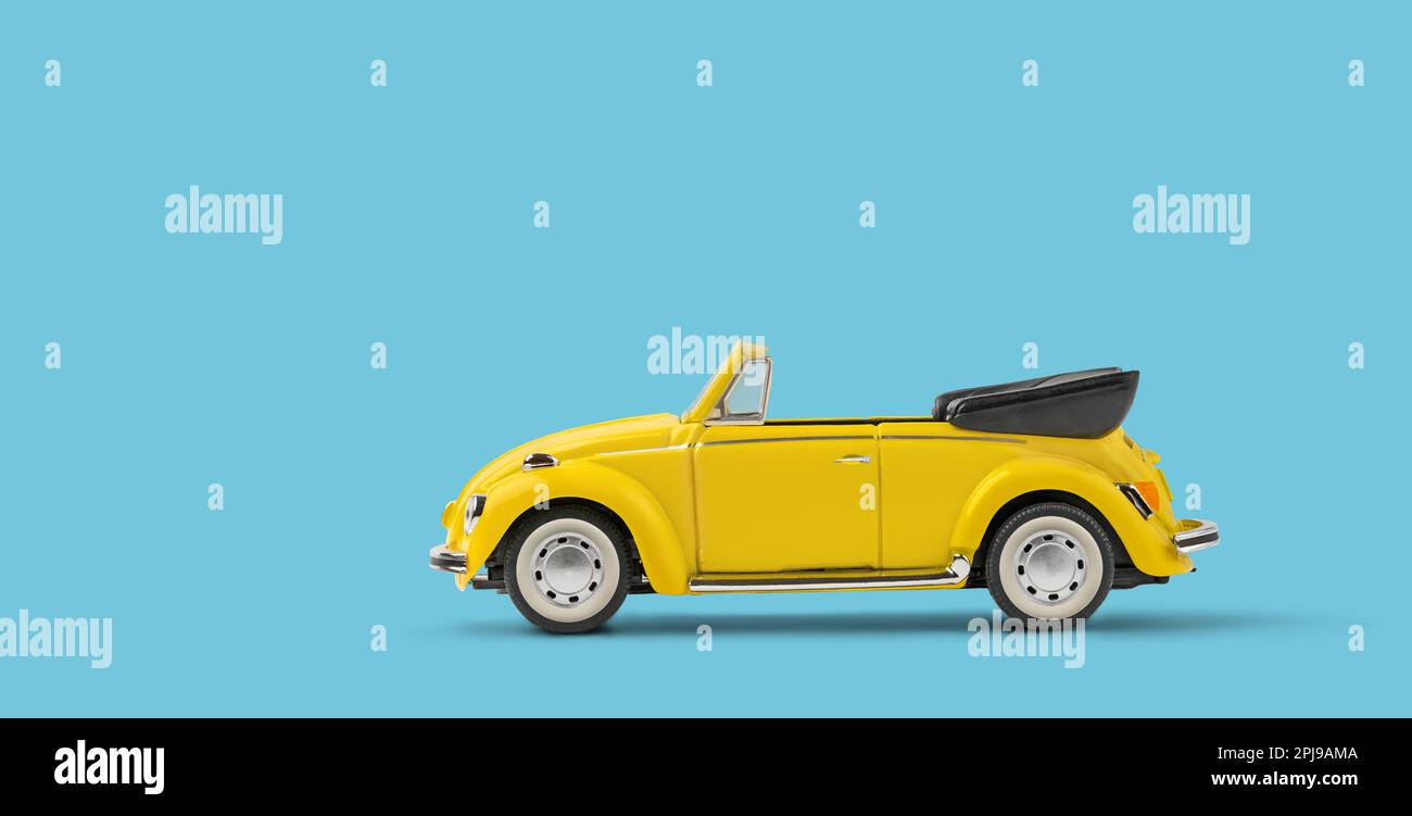 Miniature yellow toy convertible car on blue background with copyspace ...