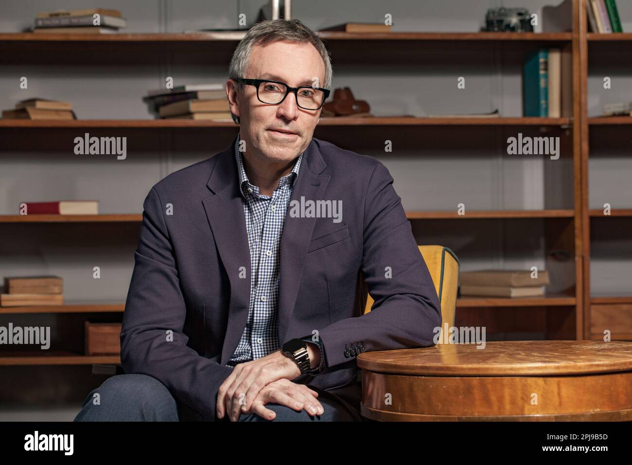 Serious mature businessman with grey hair in blue suit and glasses in ...