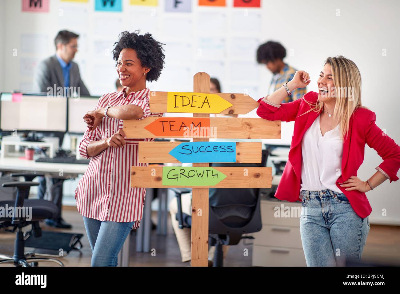 Two young cheerful female office worker are promoting company slogans ...