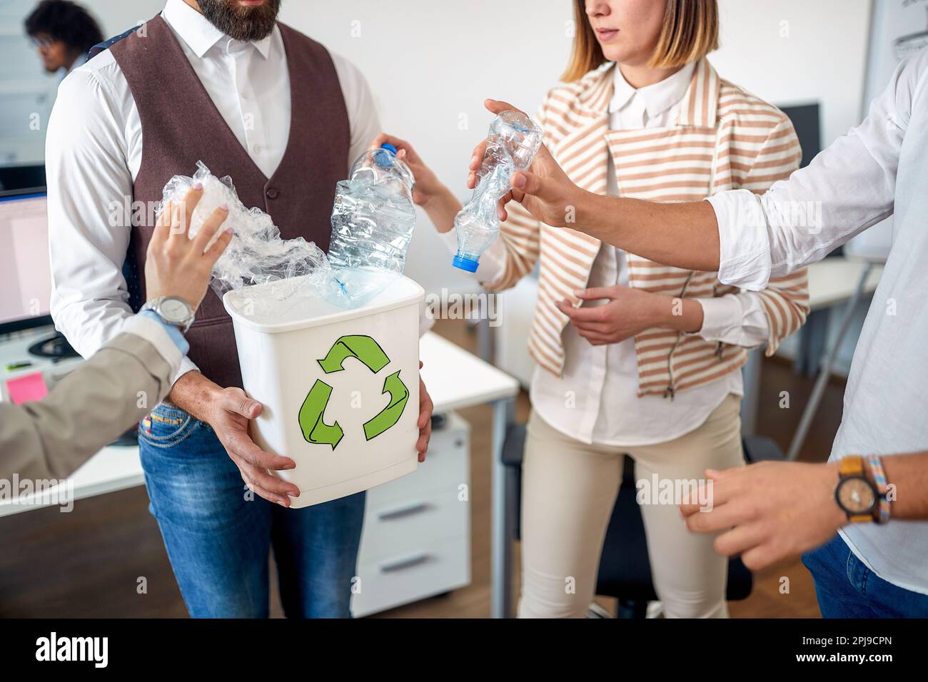A group of employees is recycling the trash by collecting it in a bin ...