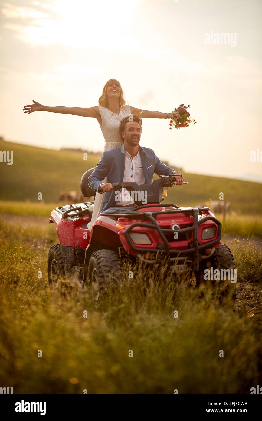 Young newlyweds are enjoying the scenery while riding the quad on a ...