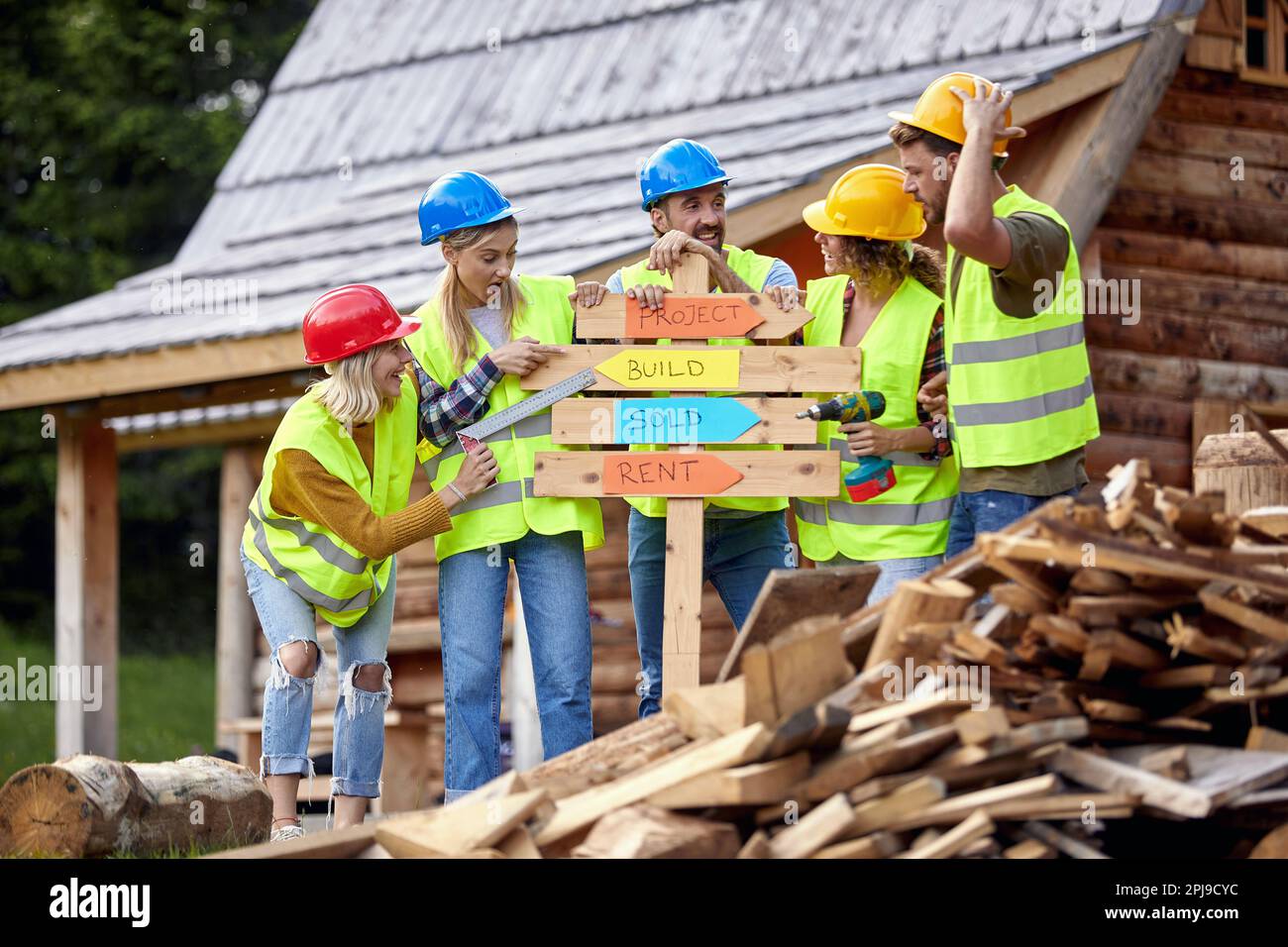 Young construction workers cheering over wooden table, group project ...