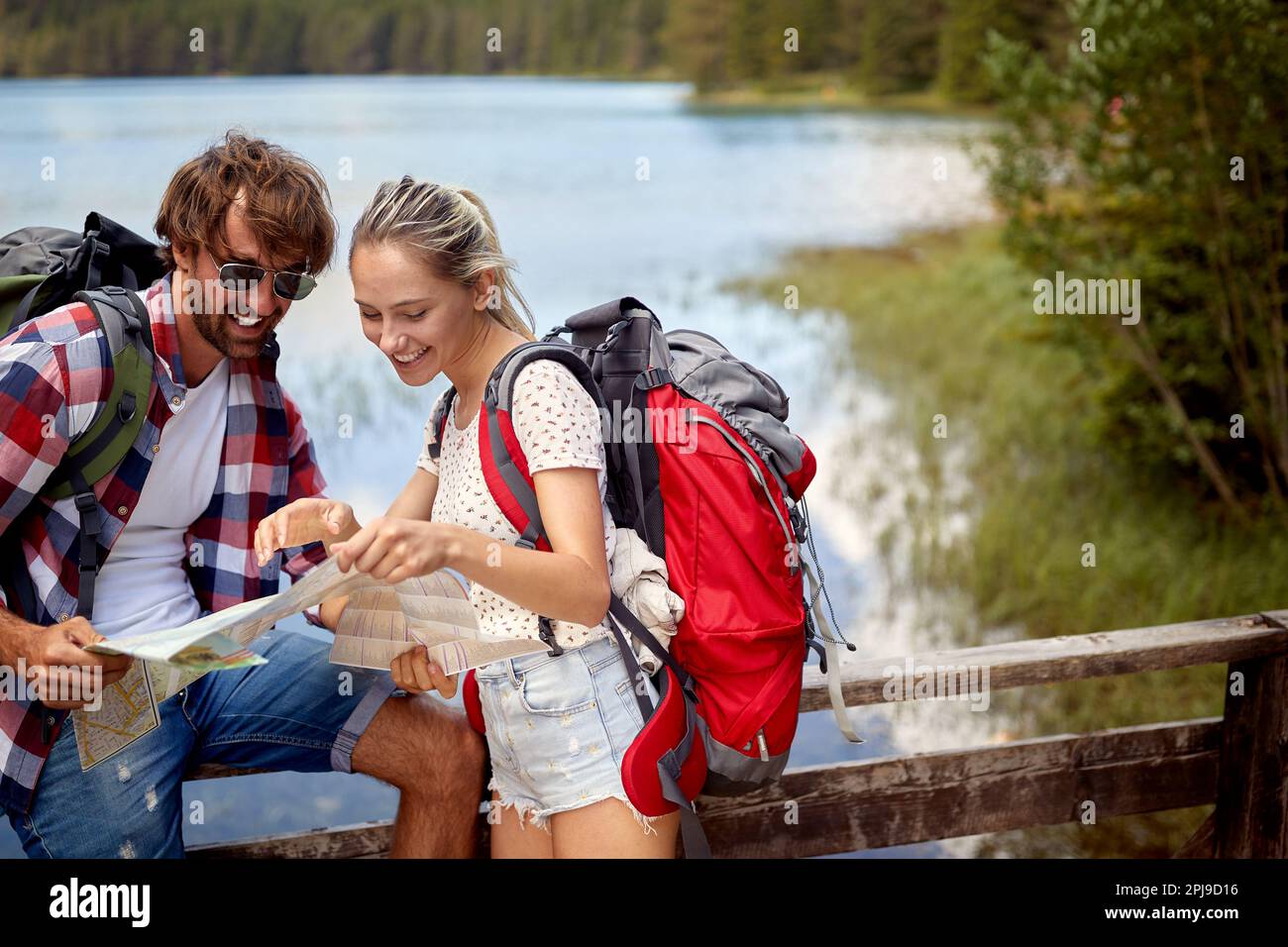 A young couple is exploring hiking map while taking a break beside the ...