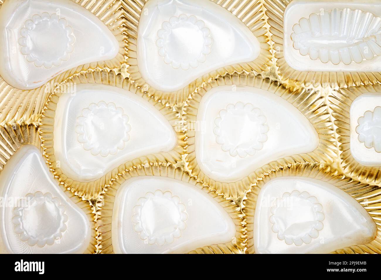 Close up shot of empty box of chocolates. Shiny gold plastic texture of ...