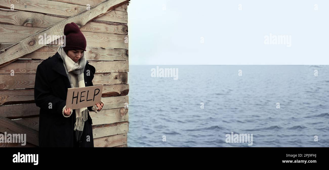 Poor young woman with HELP sign at riverside, space for text. Banner ...