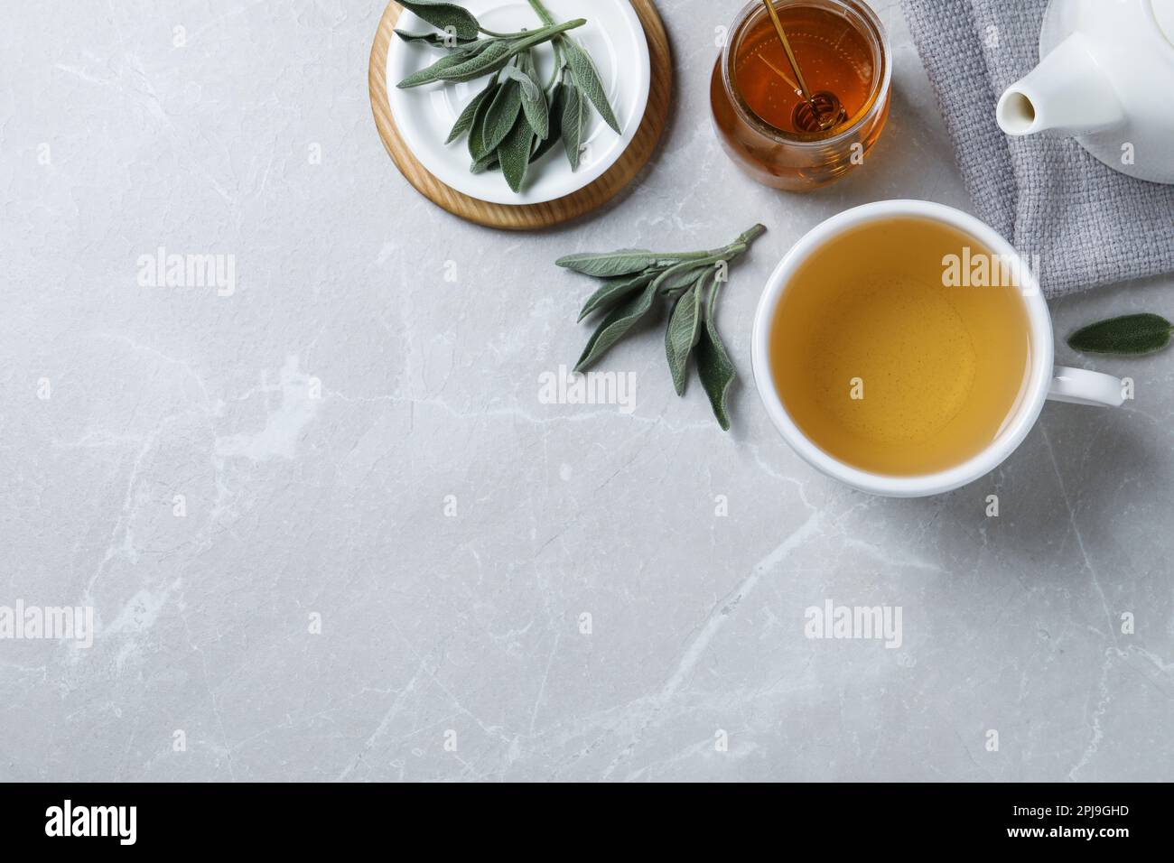 Flat lay composition with aromatic sage tea on light grey table. Space ...