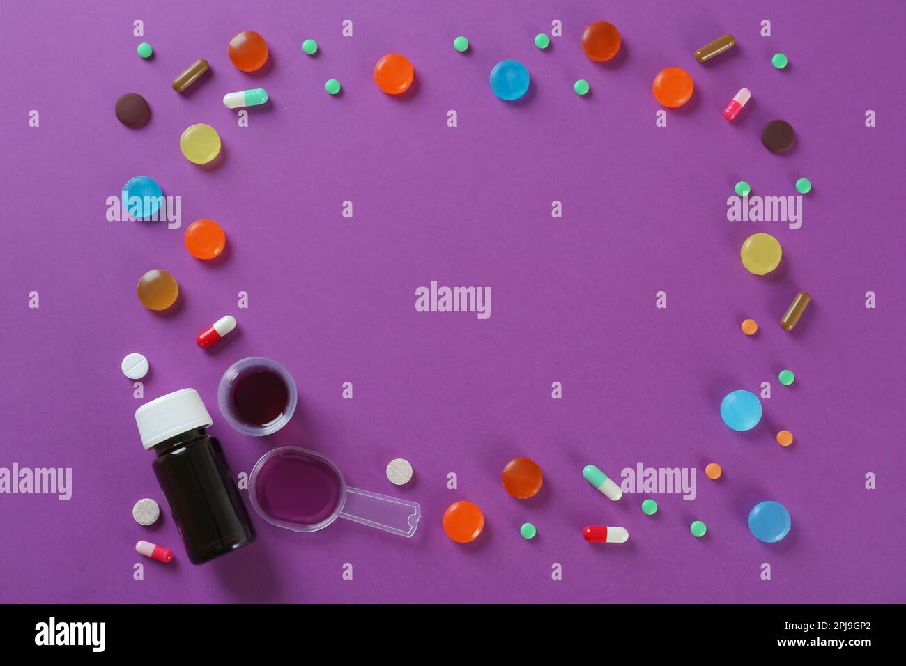 Frame made with cough drops, syrup and pills on purple background ...