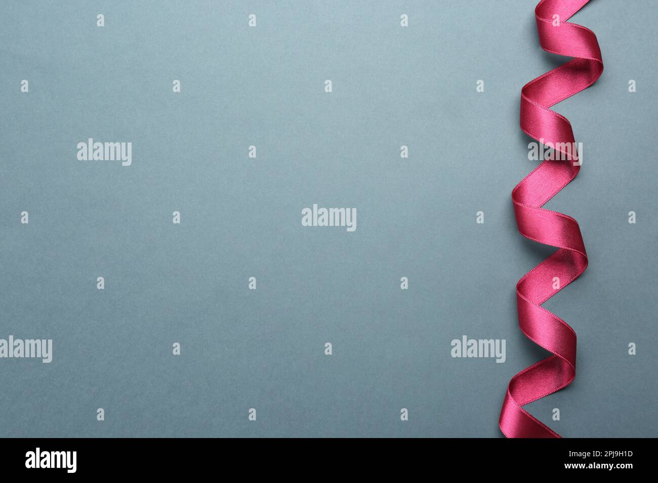 Beautiful pink ribbon on grey background, top view. Space for text ...