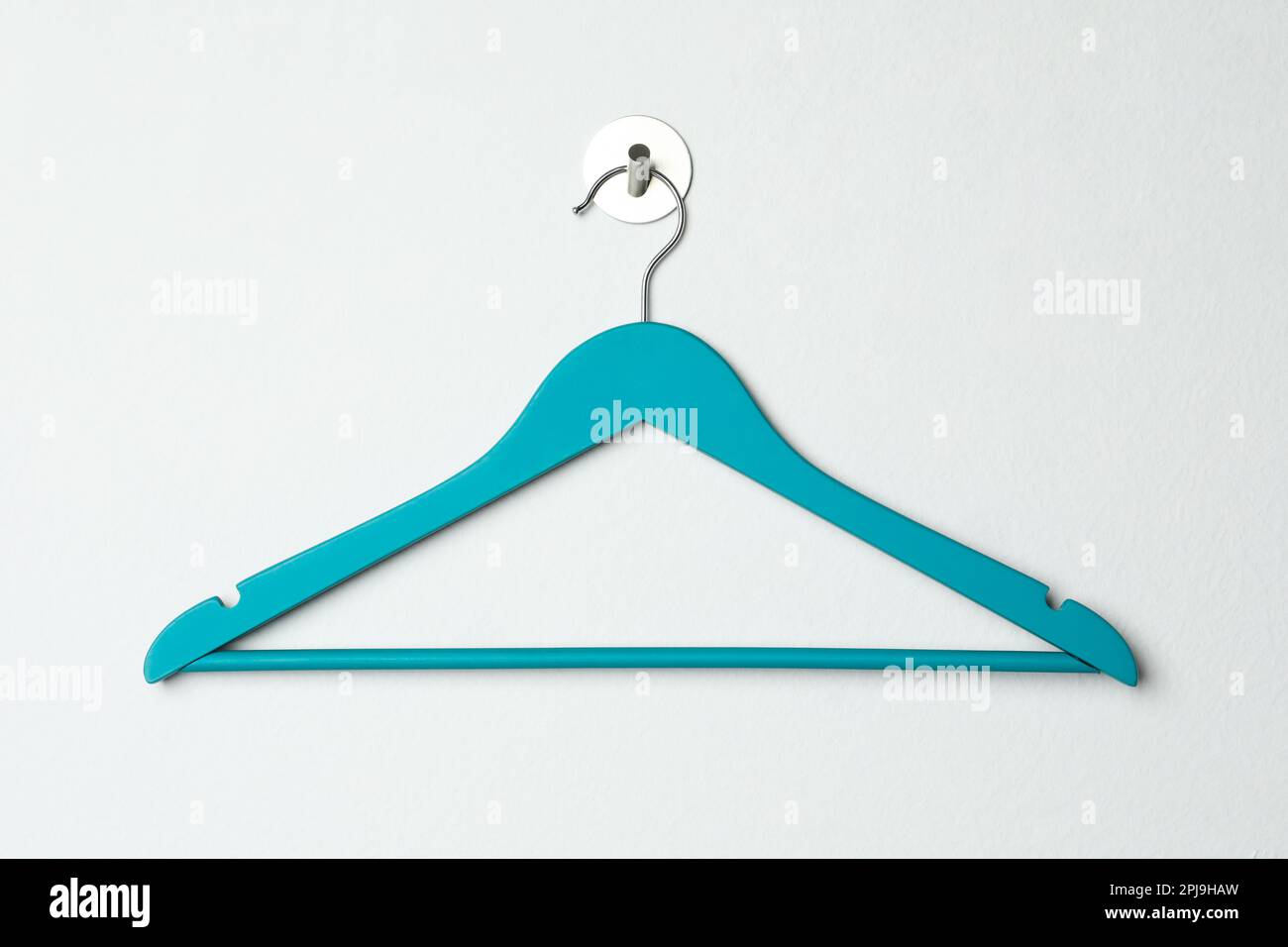 Empty turquoise clothes hanger on white wall Stock Photo - Alamy