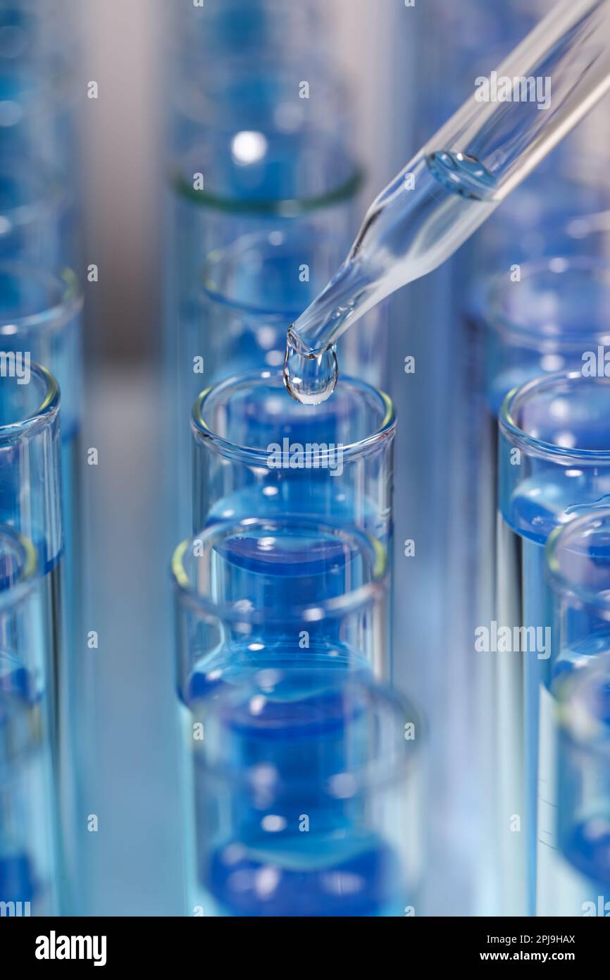 Dripping reagent into test tube with blue liquid on light background ...