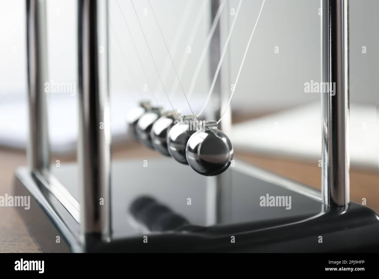 Newton's cradle on wooden table, closeup. Physics law of energy ...