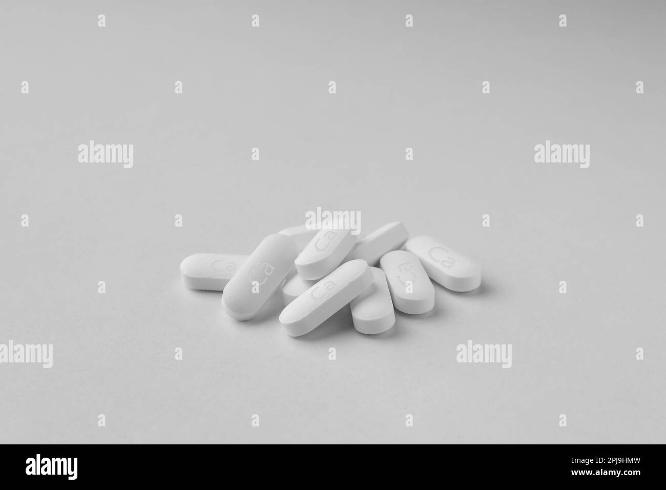Pile of calcium supplement pills on light grey background Stock Photo ...