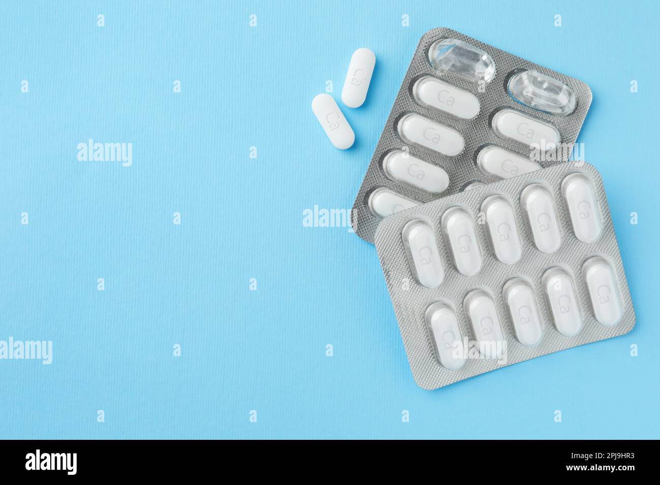 Blister packs with calcium supplement pills on light blue background ...