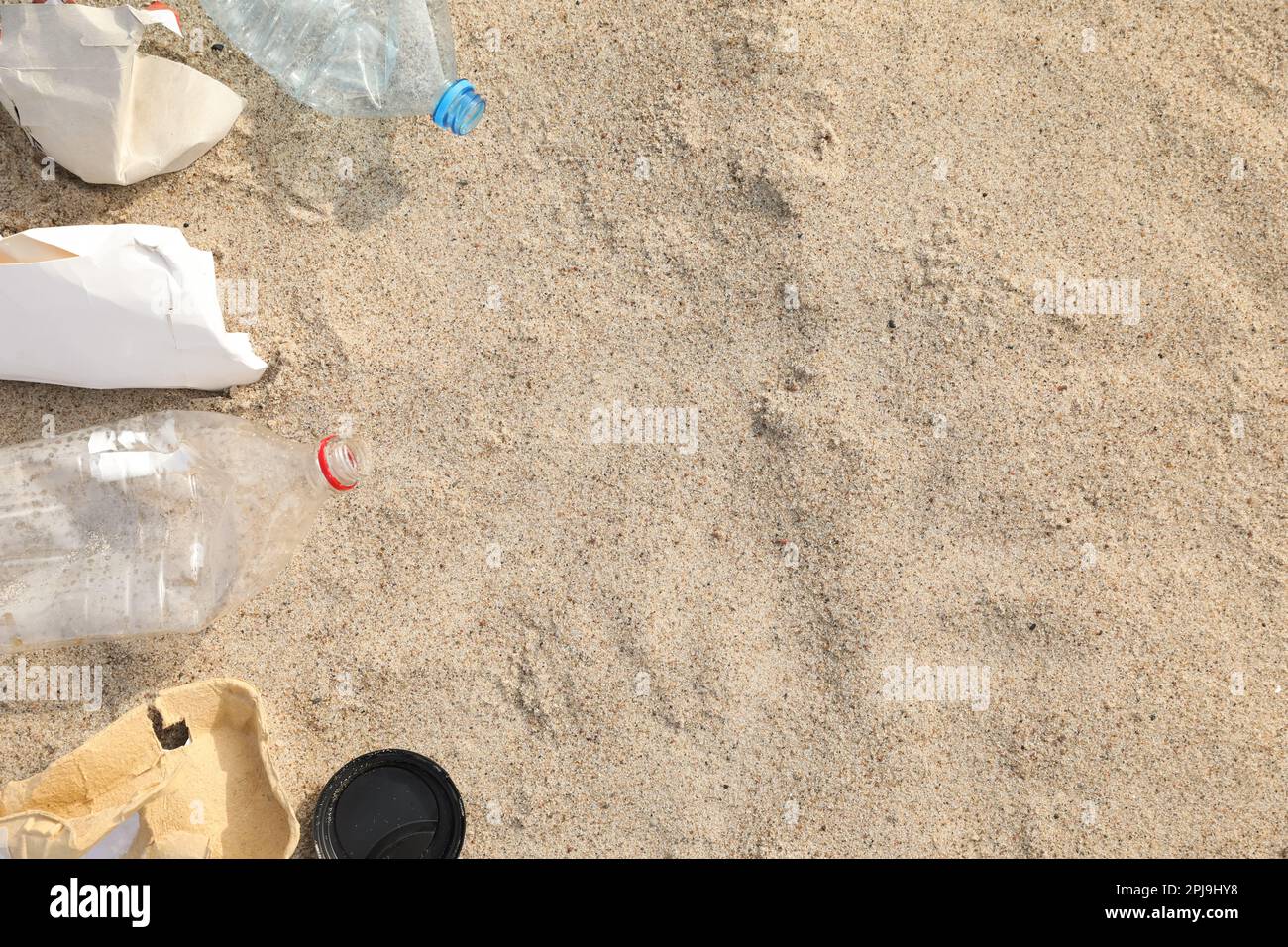 Garbage scattered on sand, flat lay with space for text. Recycling ...