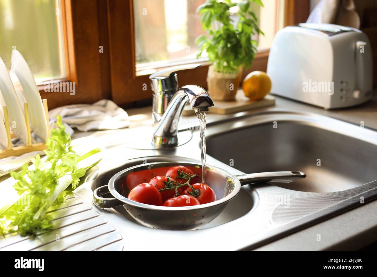 Fresh ripe tomatoes under tap water in kitchen sink Stock Photo - Alamy
