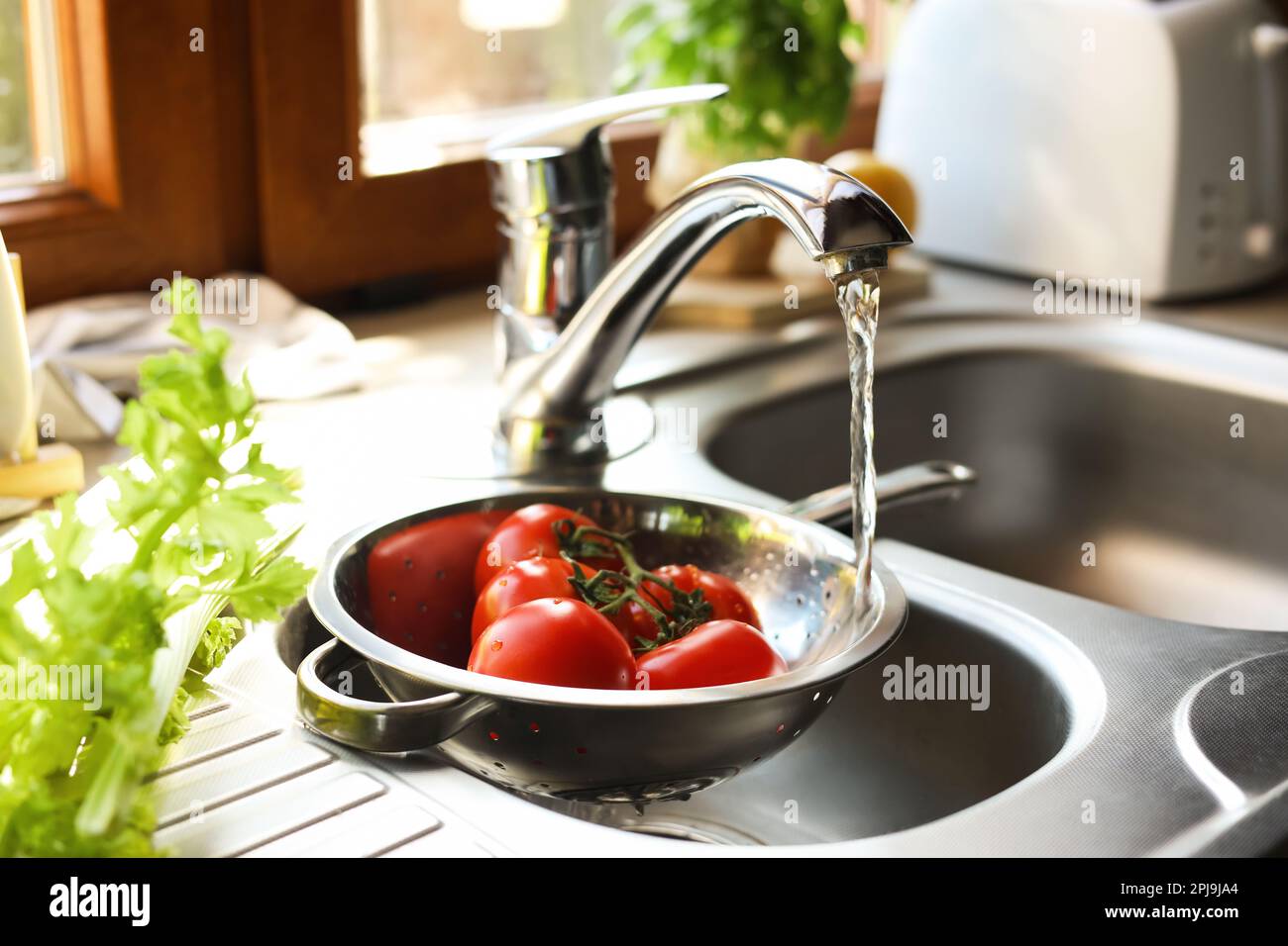 Fresh ripe tomatoes under tap water in kitchen sink Stock Photo - Alamy