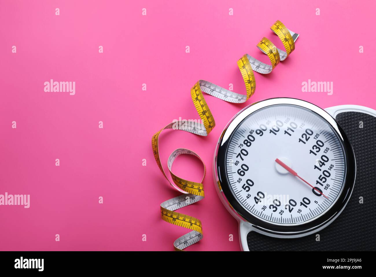 Scales and measuring tape on pink background, flat lay. Space for text ...