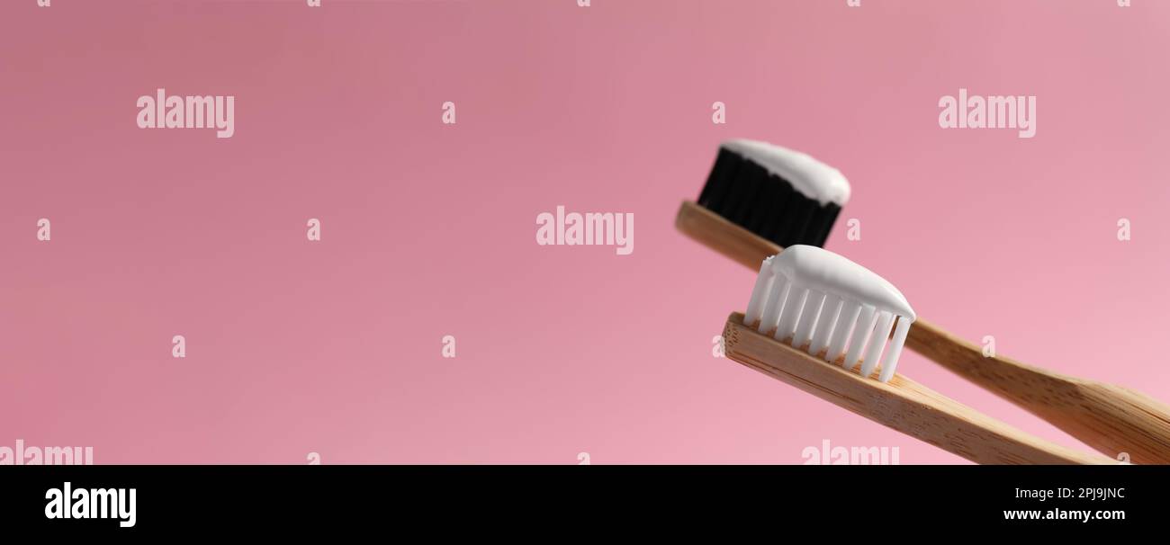 Brushes with toothpastes on pink background, space for text. Banner ...