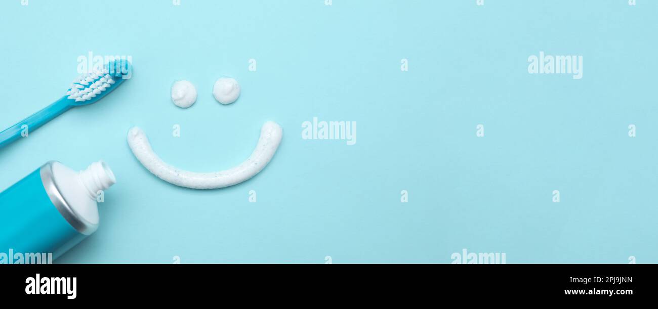 Smiling face made of toothpaste, brush and tube on light blue ...