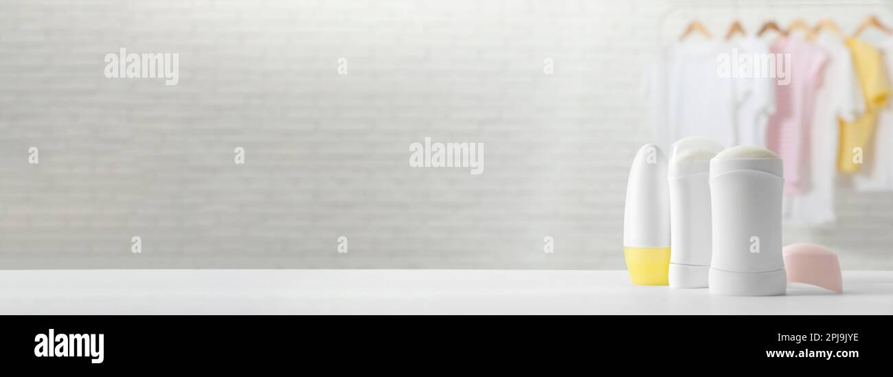 Different deodorants on white table in room, space for text. Banner ...