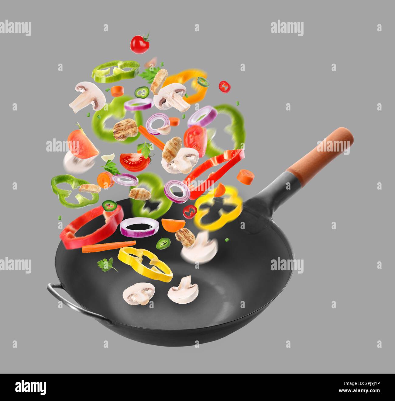Different tasty ingredients falling into wok on light grey background ...