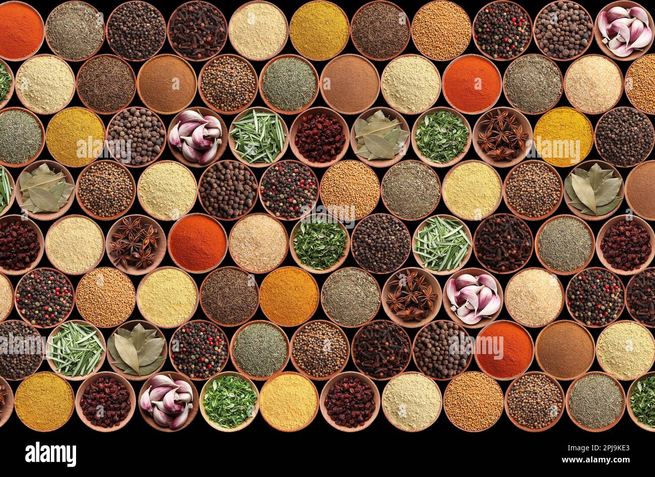 Collection of different aromatic spices and herbs on black background ...