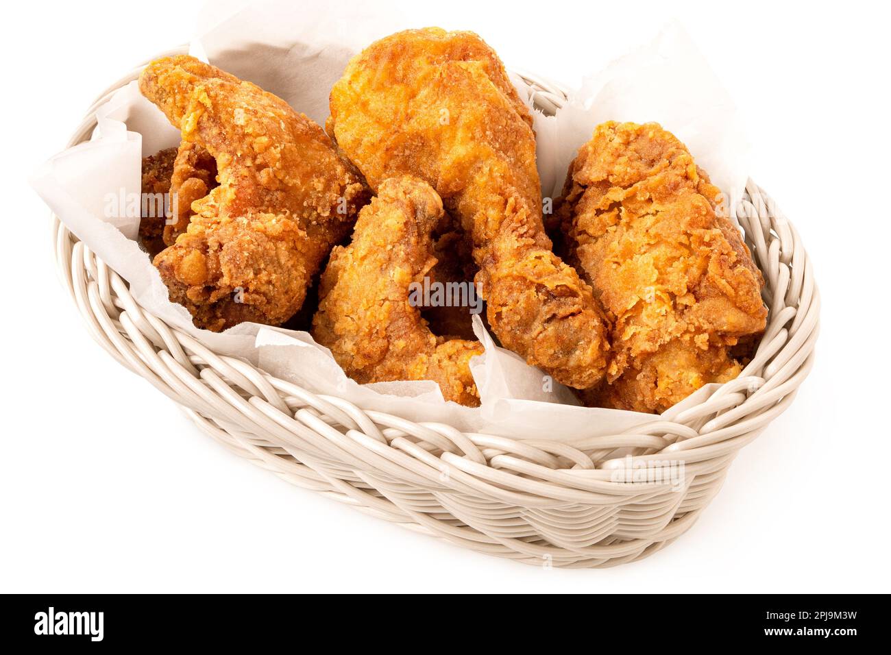 Crispy fried chicken pieces in a white woven basket isolated on white ...
