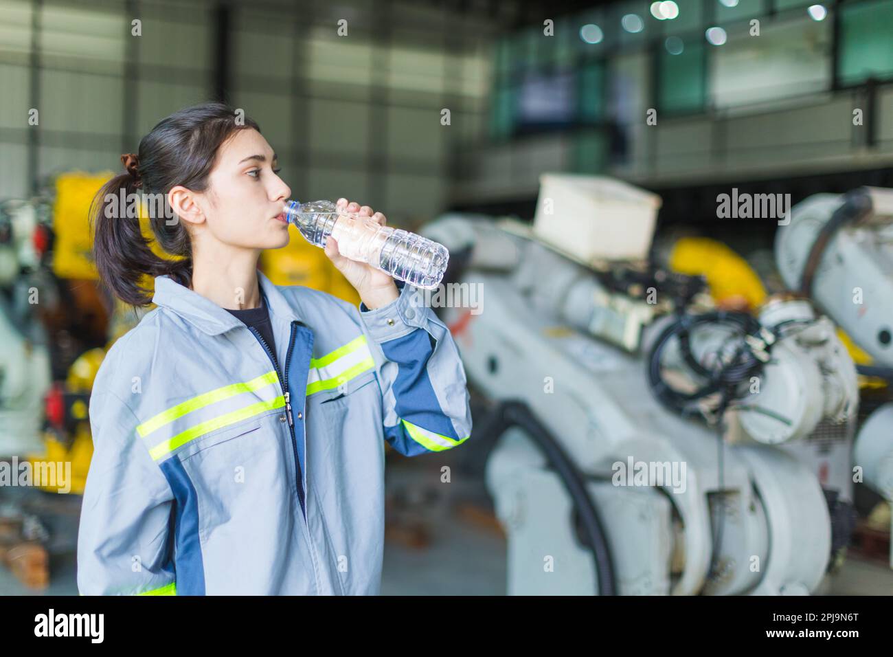 health care woman worker drinking clean water while working in factory machine warehouse for ...