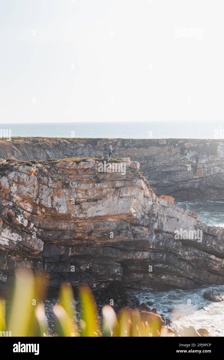 Hiker celebrates its success. Breathtaking cliffs with pebble beach in ...