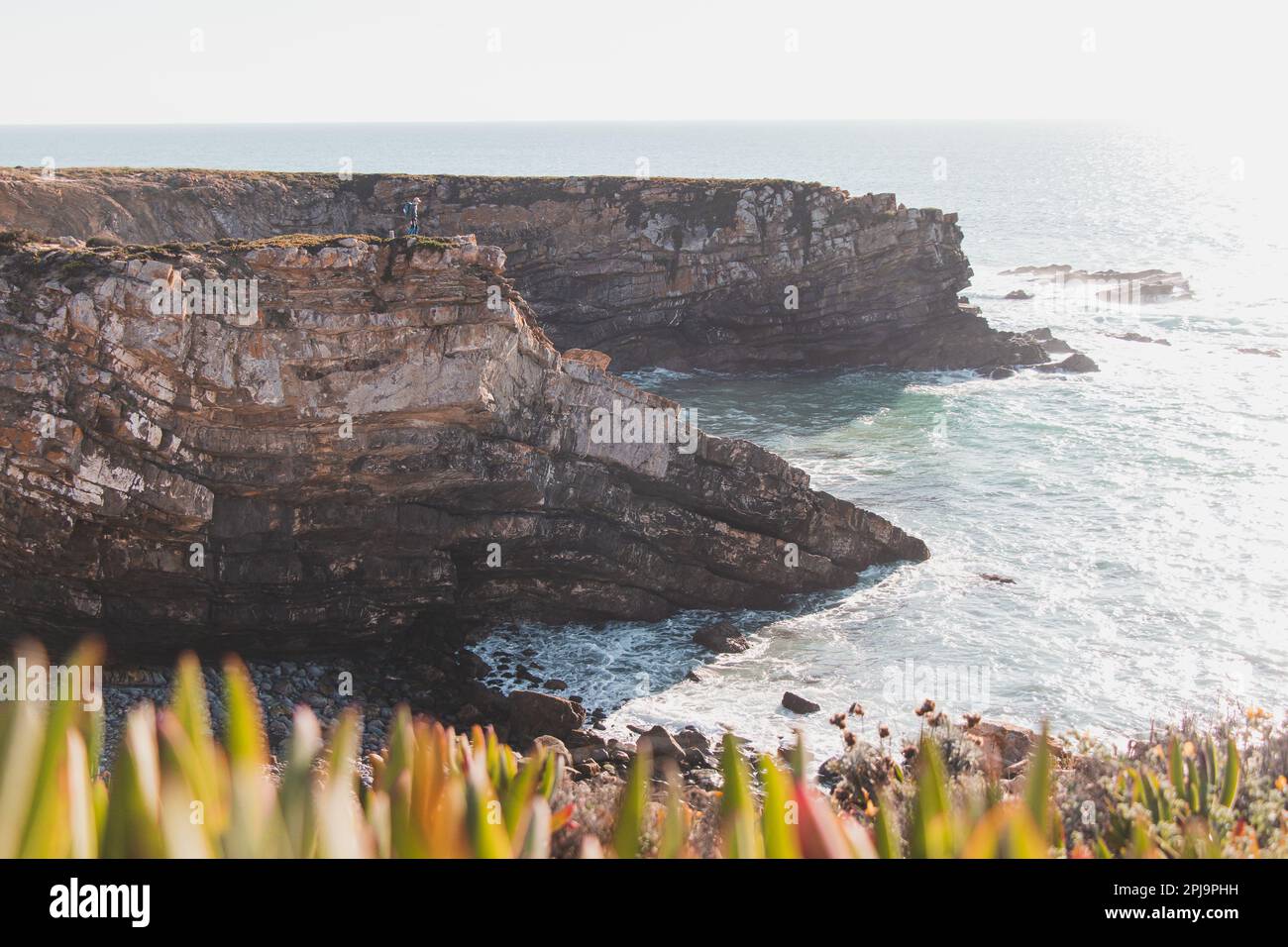Hiker celebrates its success. Breathtaking cliffs with pebble beach in ...