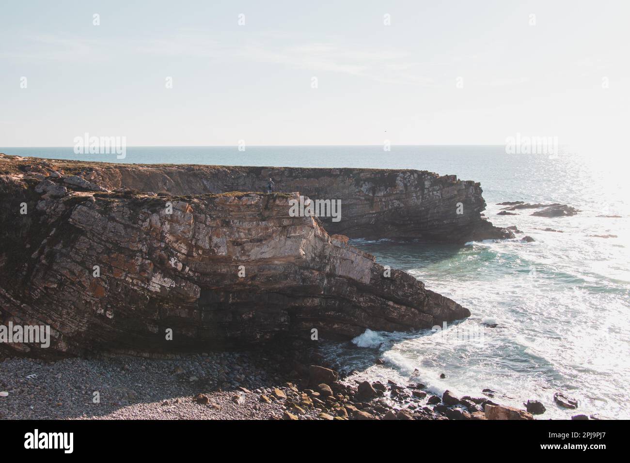 Hiker celebrates its success. Breathtaking cliffs with pebble beach in ...