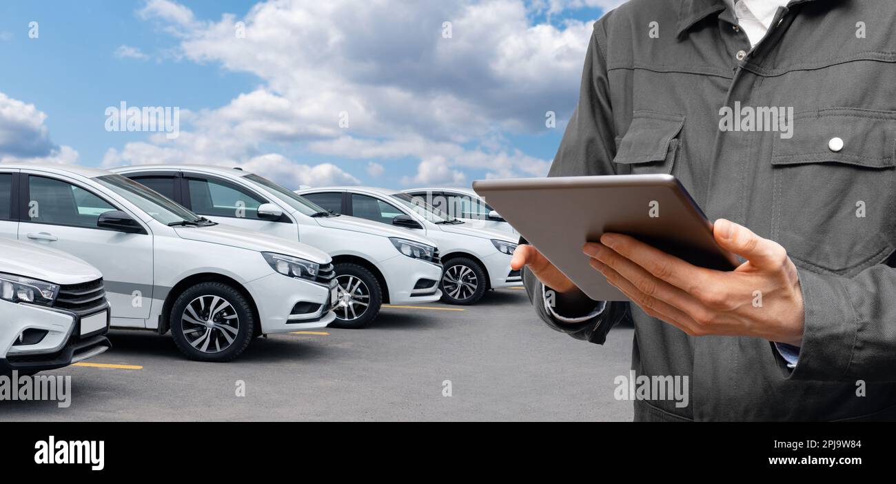 Manager with digital tablet on a background of rows of cars. Car sales ...