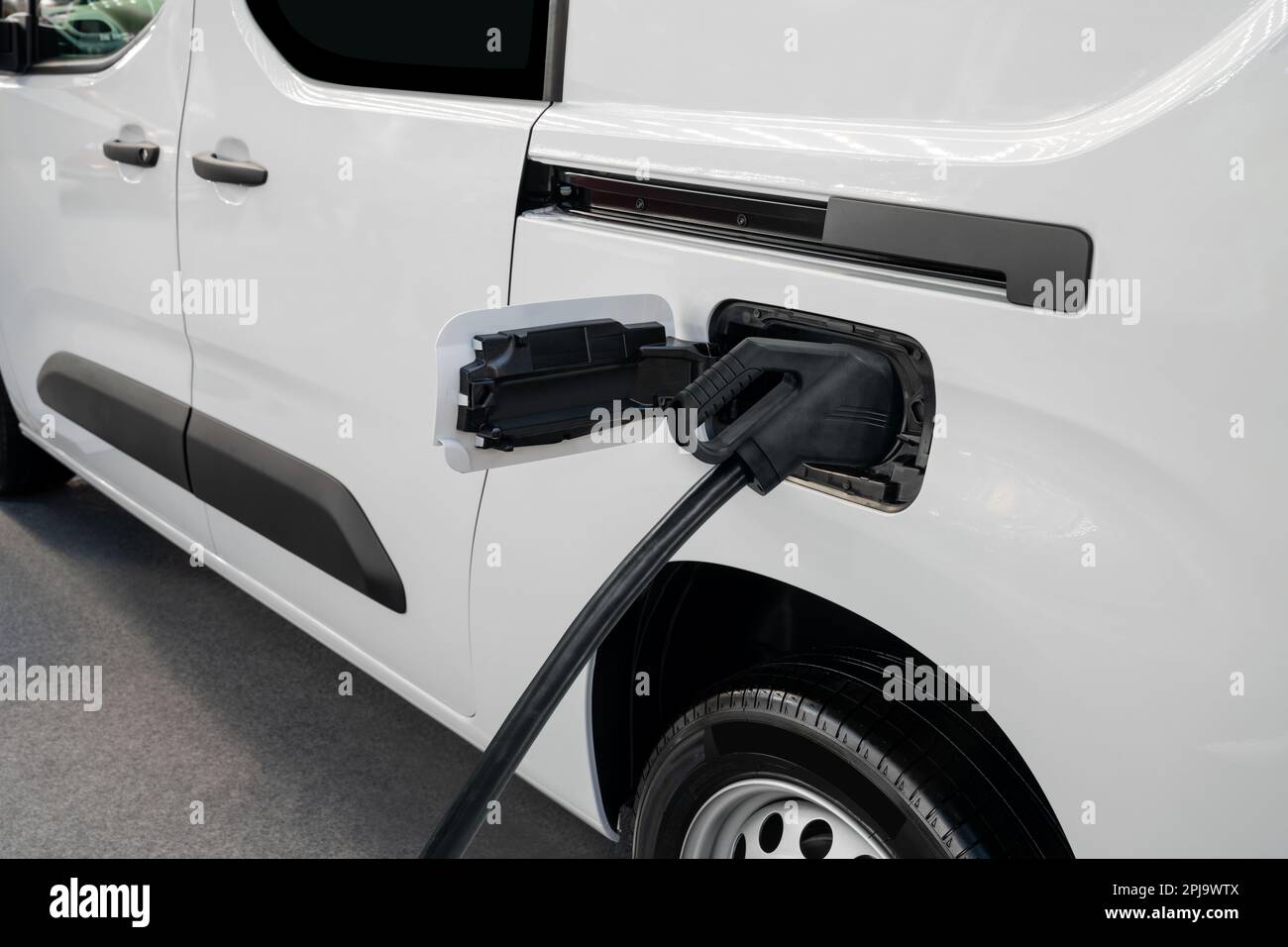 Electric delivery van with connected charging cable. High quality photo ...