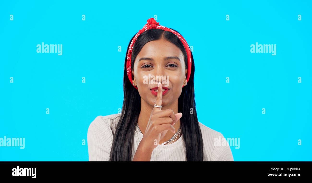 Secret, face and happy woman with finger on lips in studio, blue ...