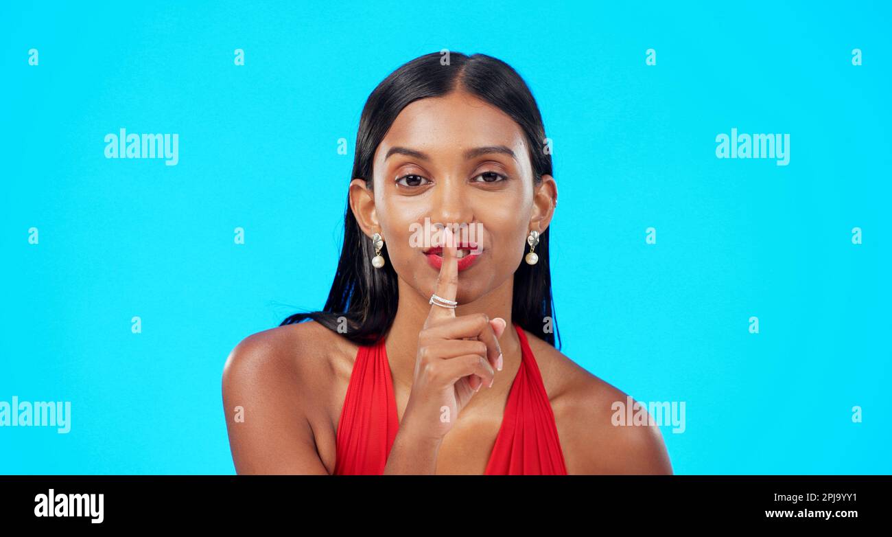 Secret, face and woman with finger on lips in studio, blue background ...